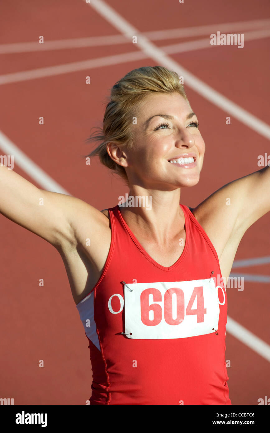Woman running on track with arms raised in victory Stock Photo - Alamy