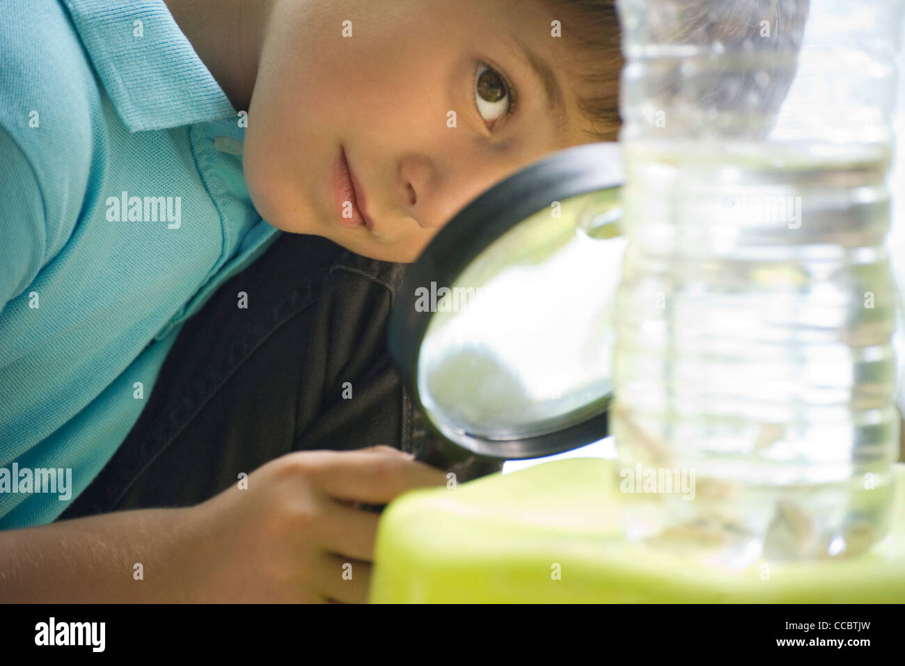 Boy studying bottle of water with magnifying glass Stock Photo - Alamy