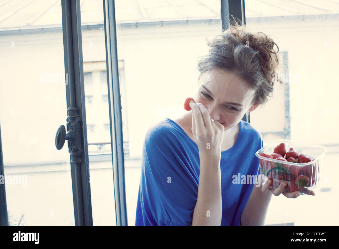 Mid-adult woman laughing while eating strawberries Stock Photo - Alamy