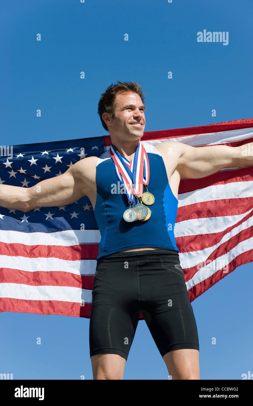 Male athlete on winner's podium, holding up American flag Stock Photo ...