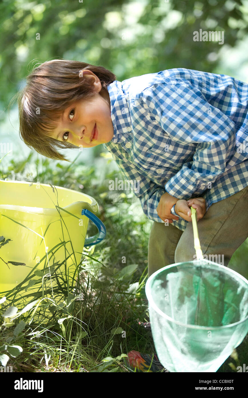 Boy leaning over bucket with fishing net in hands Stock Photo - Alamy