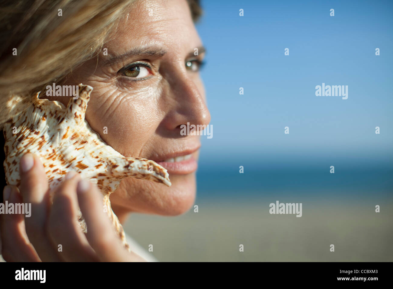 Woman listening to seashell Stock Photo - Alamy