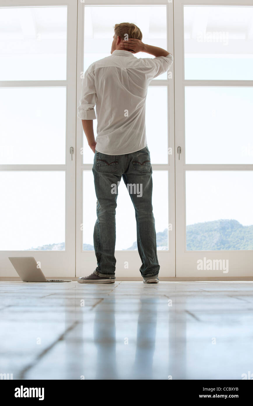 Man looking out window, rear view Stock Photo - Alamy