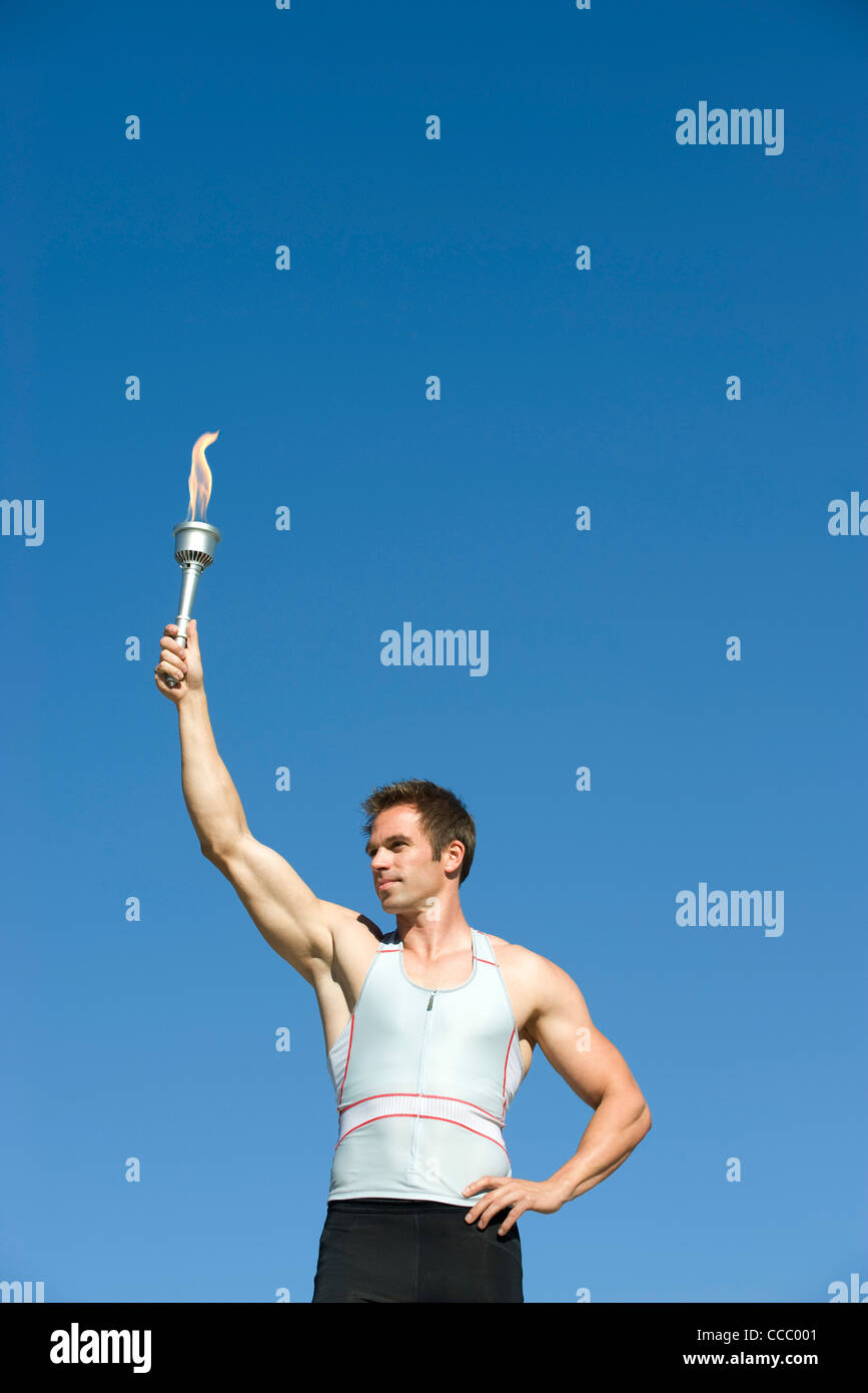 Male athlete holding up torch Stock Photo - Alamy
