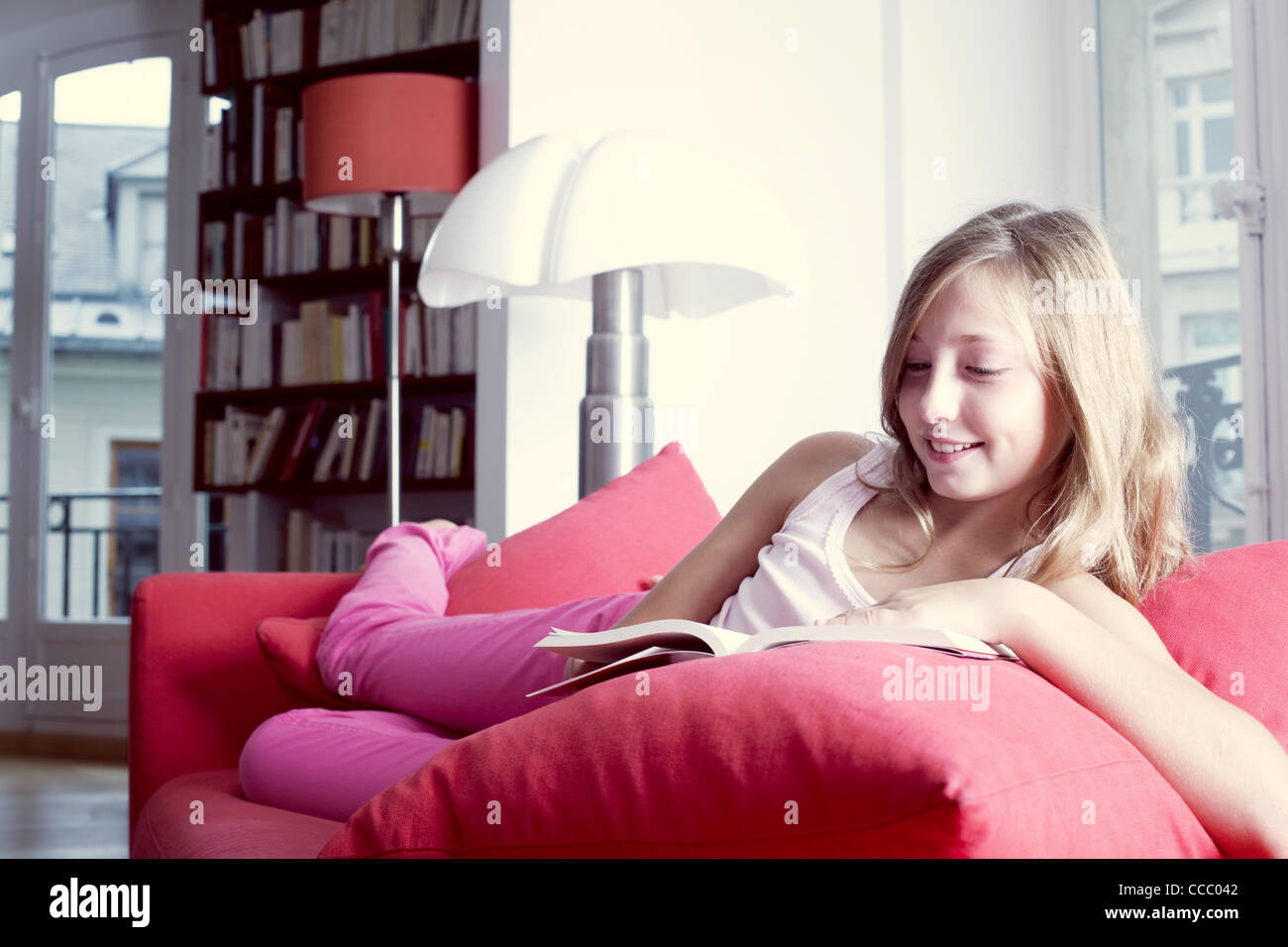 Girl relaxing on couch reading book Stock Photo - Alamy