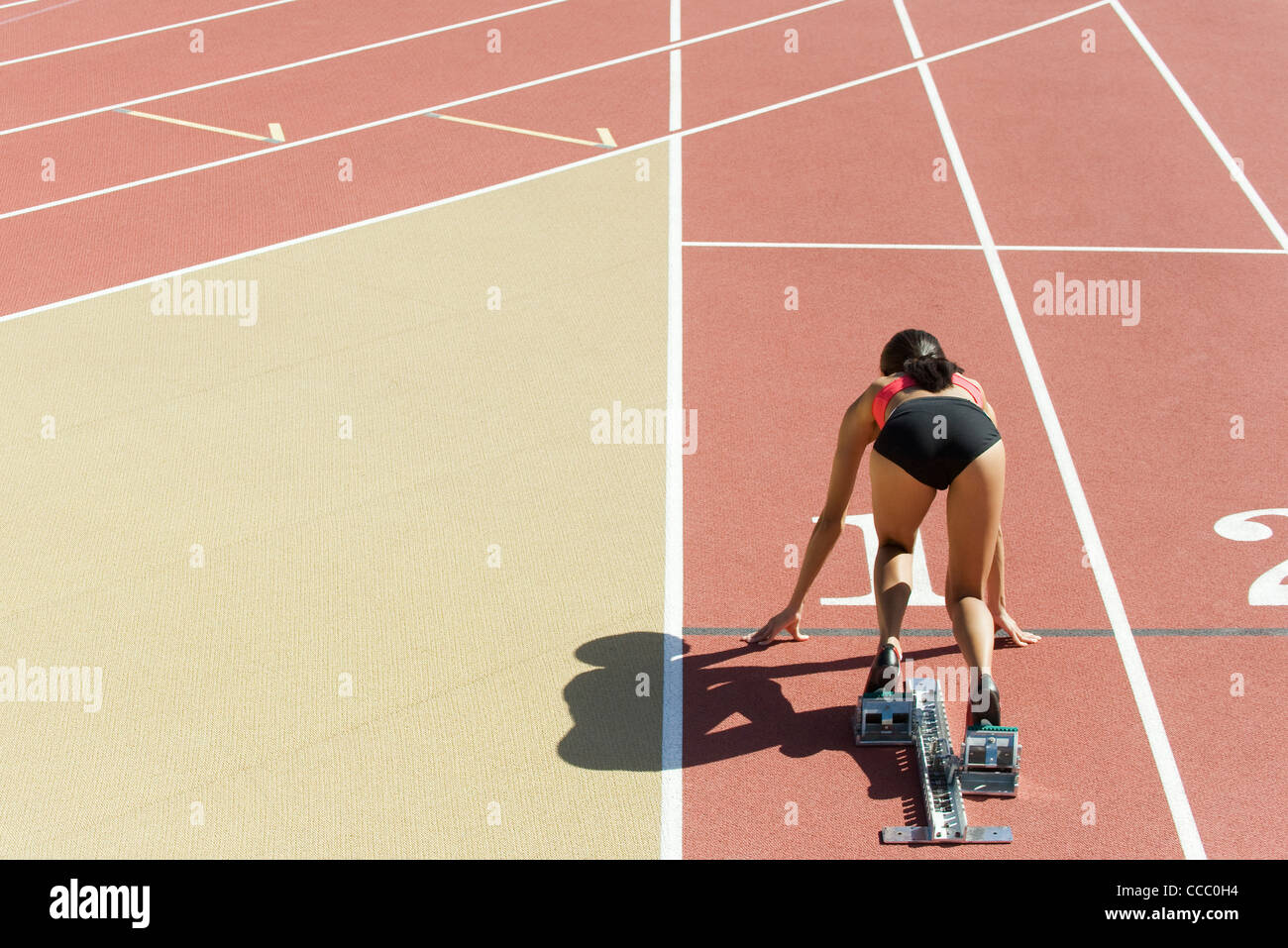 Woman crouched in starting position on running track, rear view Stock ...