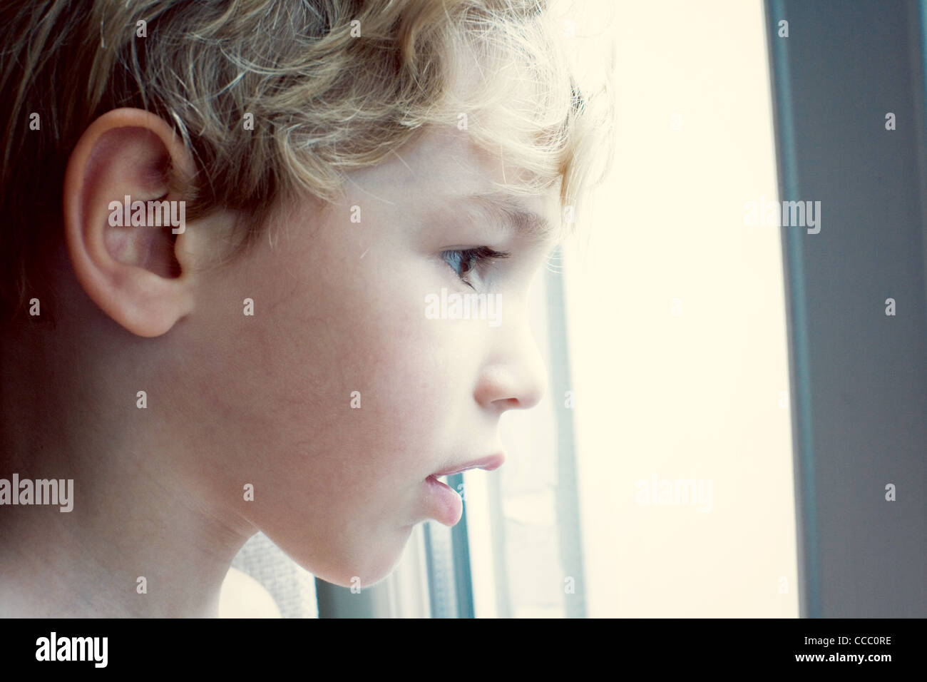 Little boy looking out of window Stock Photo - Alamy