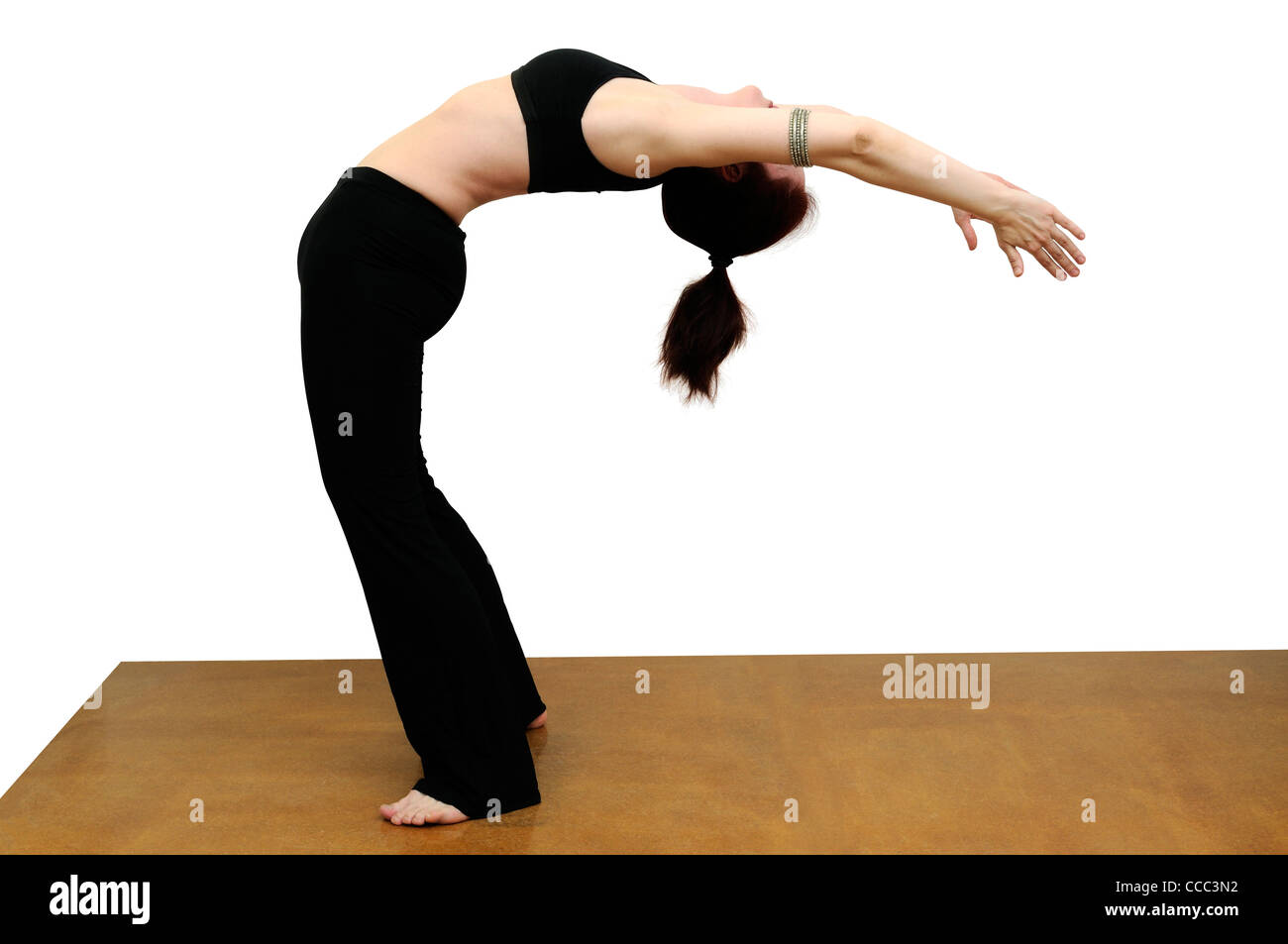 Woman practicing yoga and making back-bend on a brown floor, isolated ...