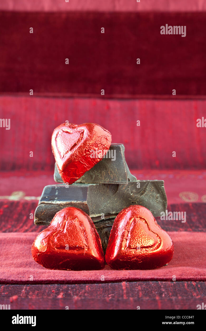 Red foil wrapped candy hearts arranged on top of pile of gourmet thick ...