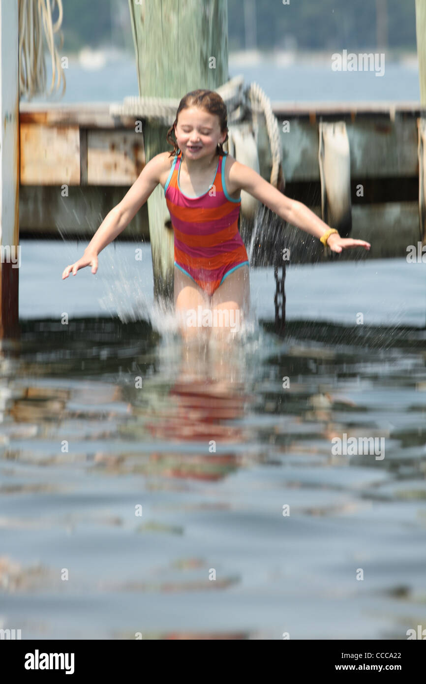 front view of girl jump entering water from pier Stock Photo - Alamy