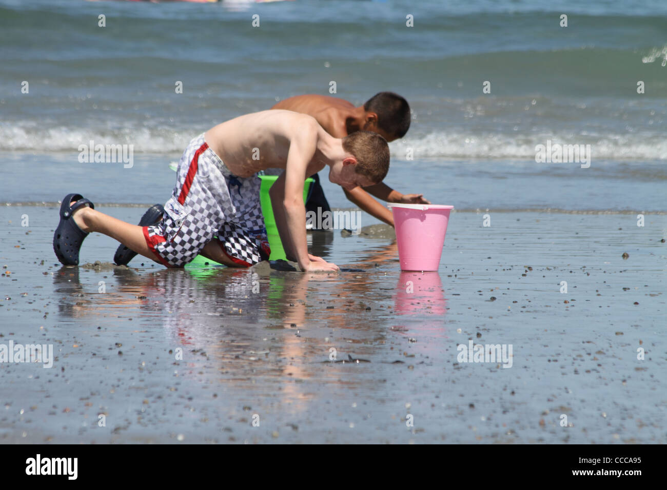 digging in wet sand reflection daytime ocean waves on beach Stock Photo ...