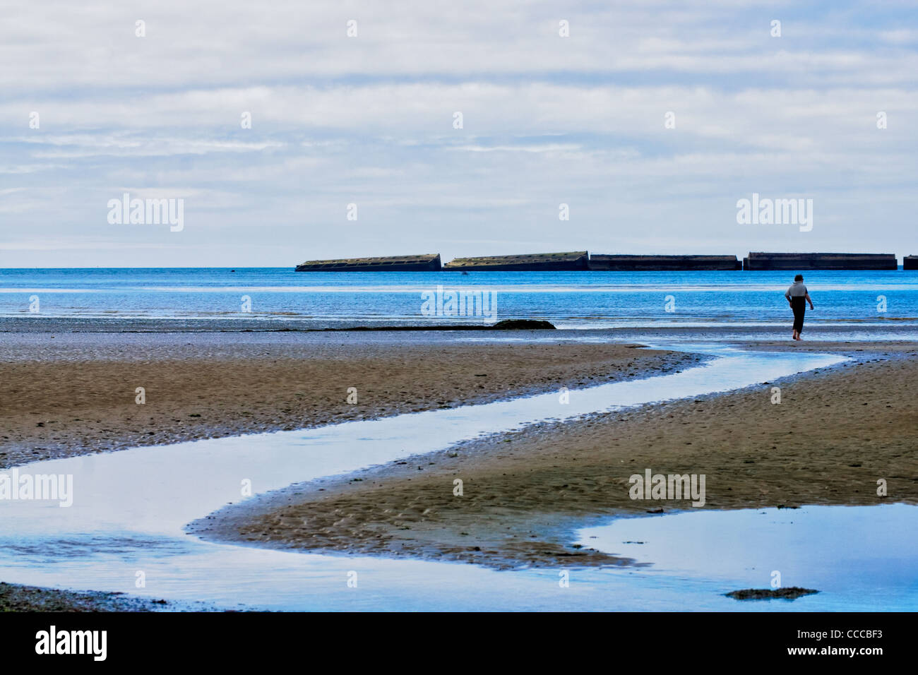 Arromanche, Normandy, France. A man walks on the seashort. Remnants of ...