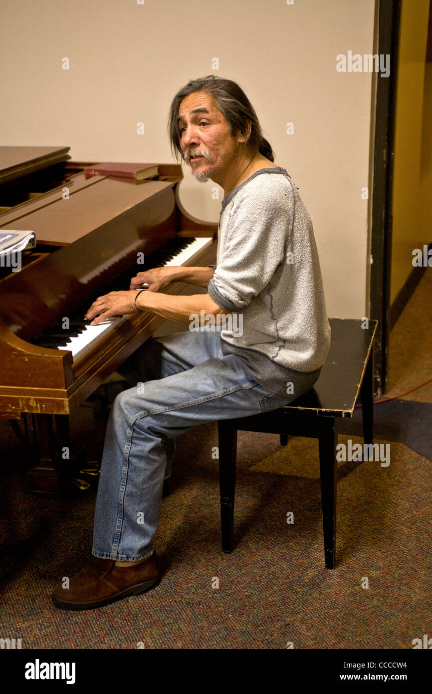 A homeless man plays the piano and sings at a night shelter held at a ...