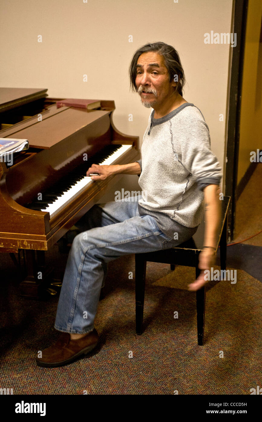 A homeless man plays the piano and sings at a night shelter held at a ...