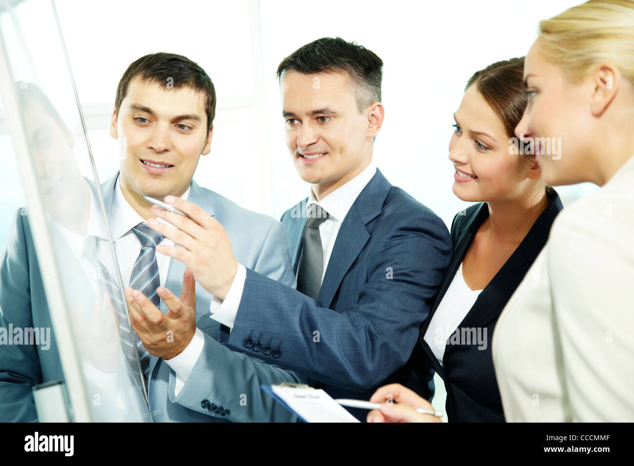A business man explaining something on a whiteboard to his partners ...