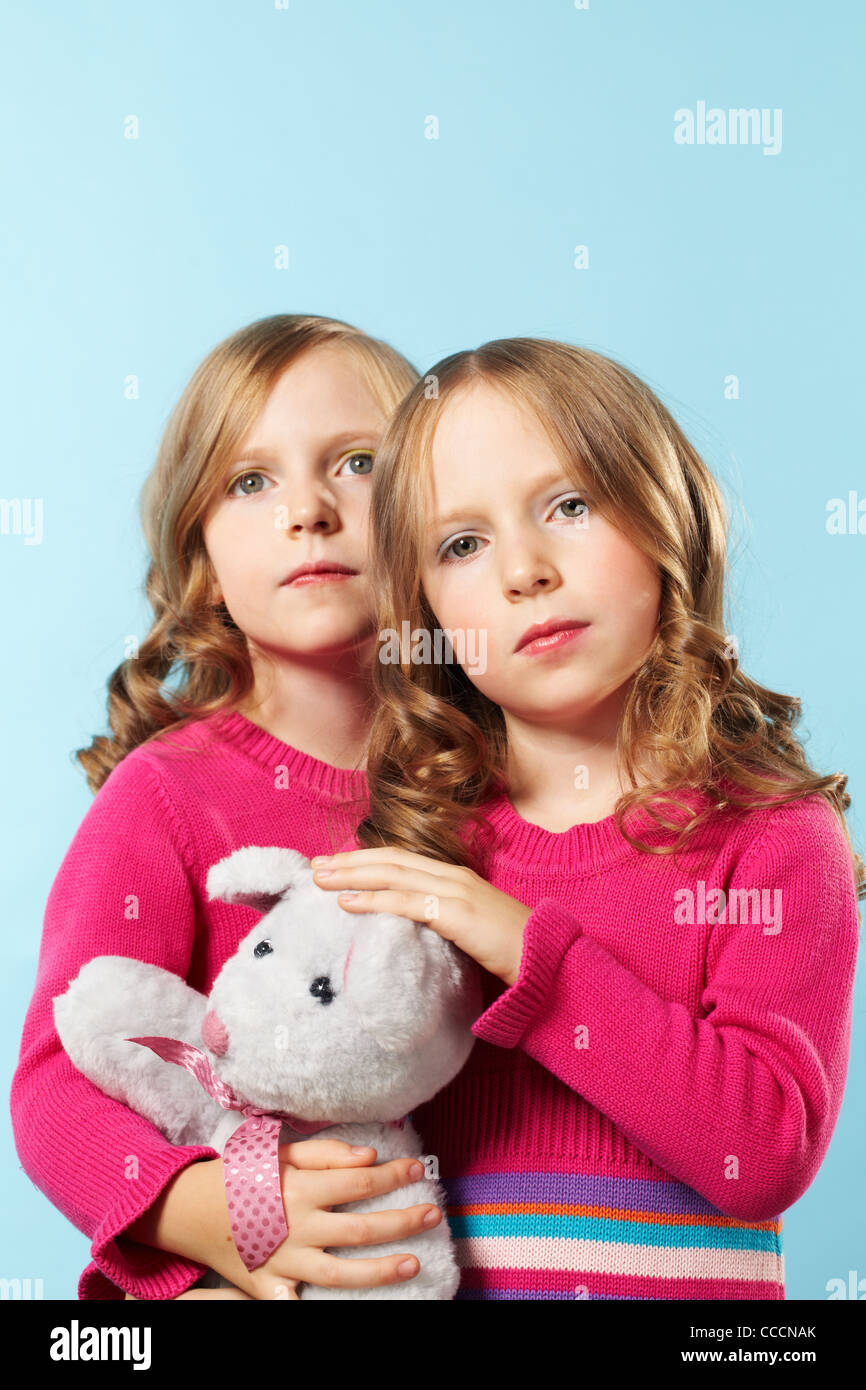 Portrait of twins in crimson clothes against blue background Stock ...