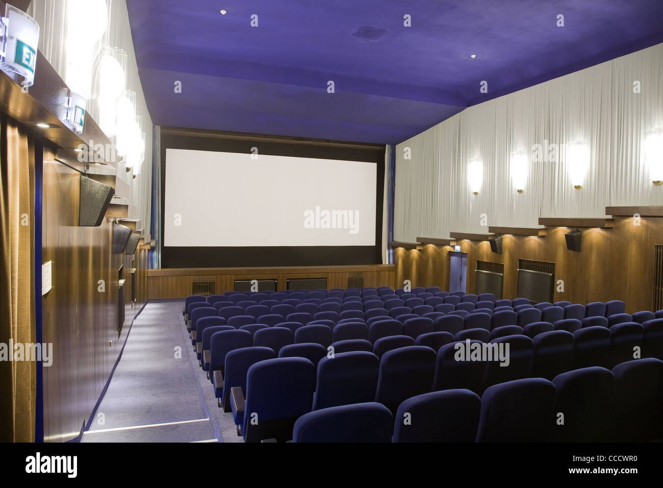 Empty cinema auditorium with line of chairs and projection screen ...
