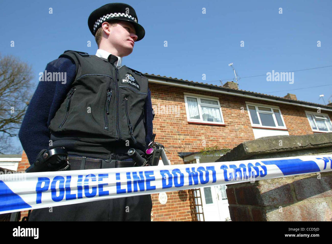 A policeman guards a property. Police Line do not cross tape. Picture ...