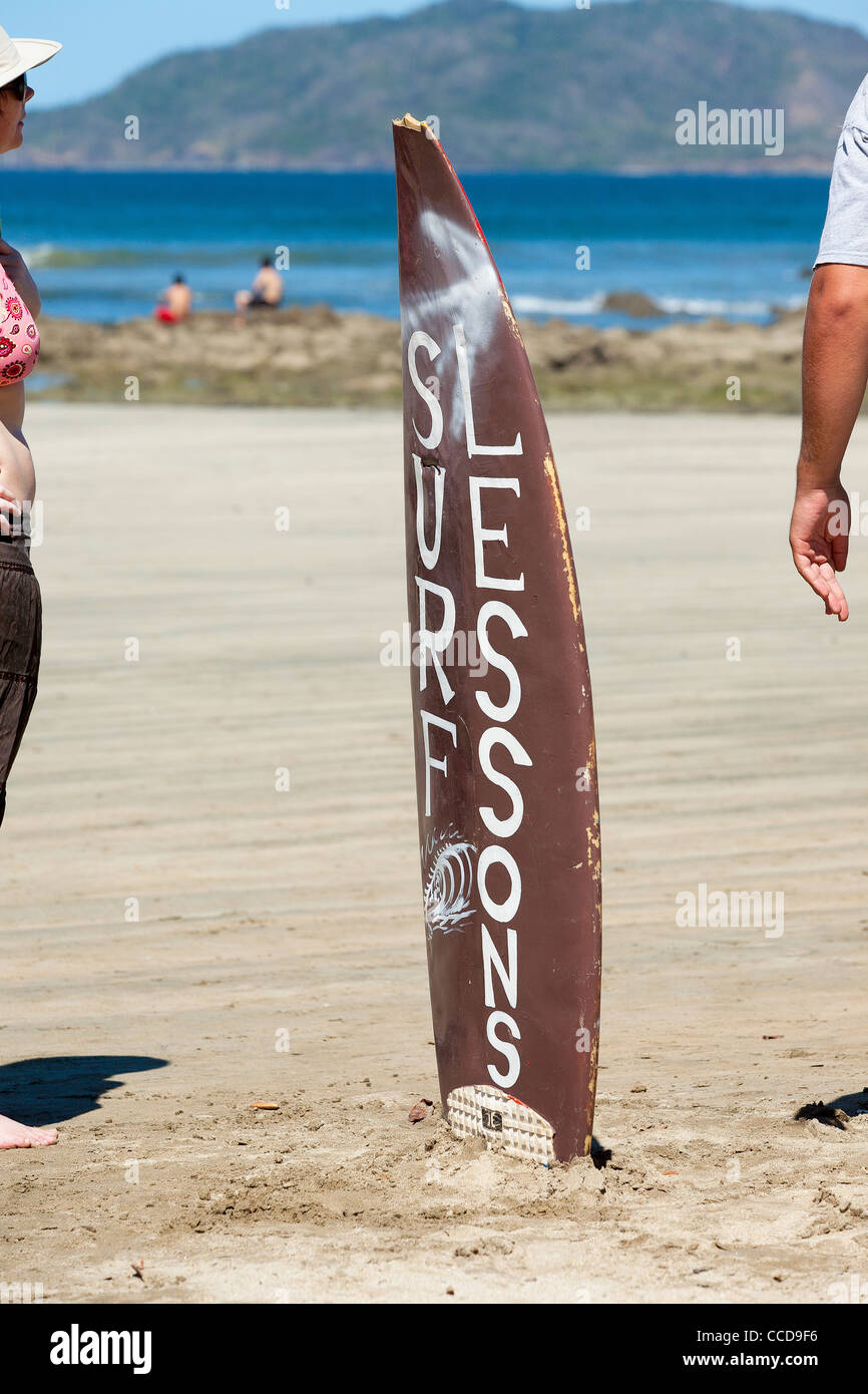 A sign painted on a surfboard advertising surf lessons in Tamarindo ...