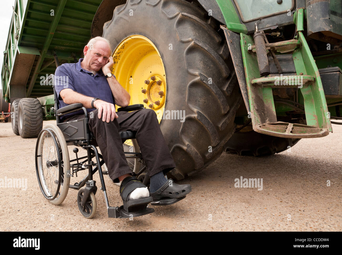 A man in a wheelchair beside an agricultural tractor and trailer Stock ...