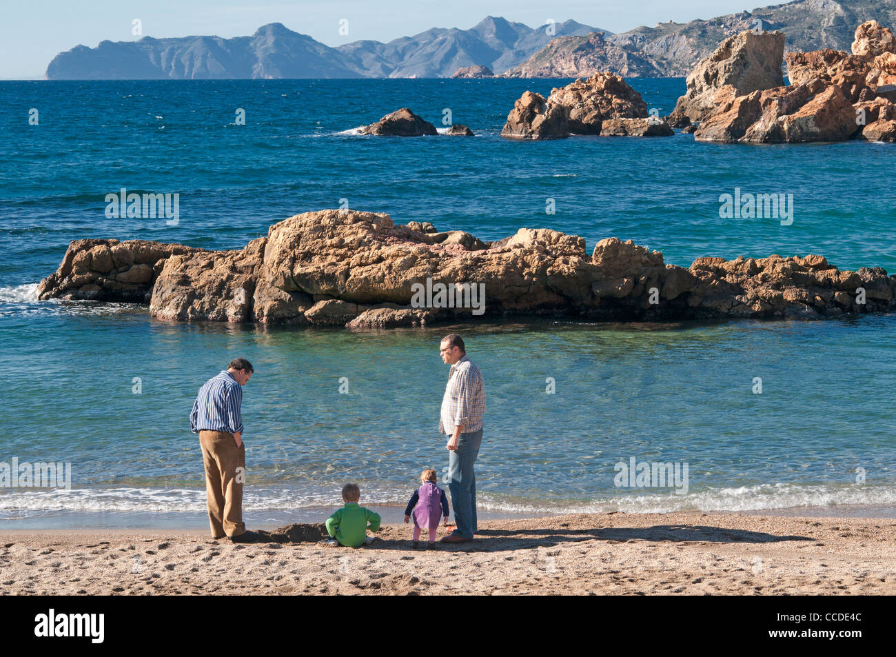 Family enjoying the December winter sunshine, Cala Cortina Beach, Costa ...