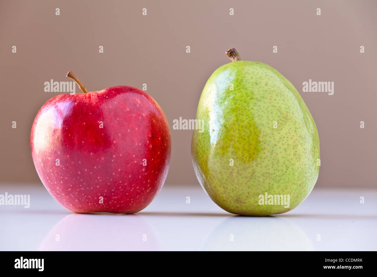 Two pieces of fruits - red apple and green pear - on white with taupe ...