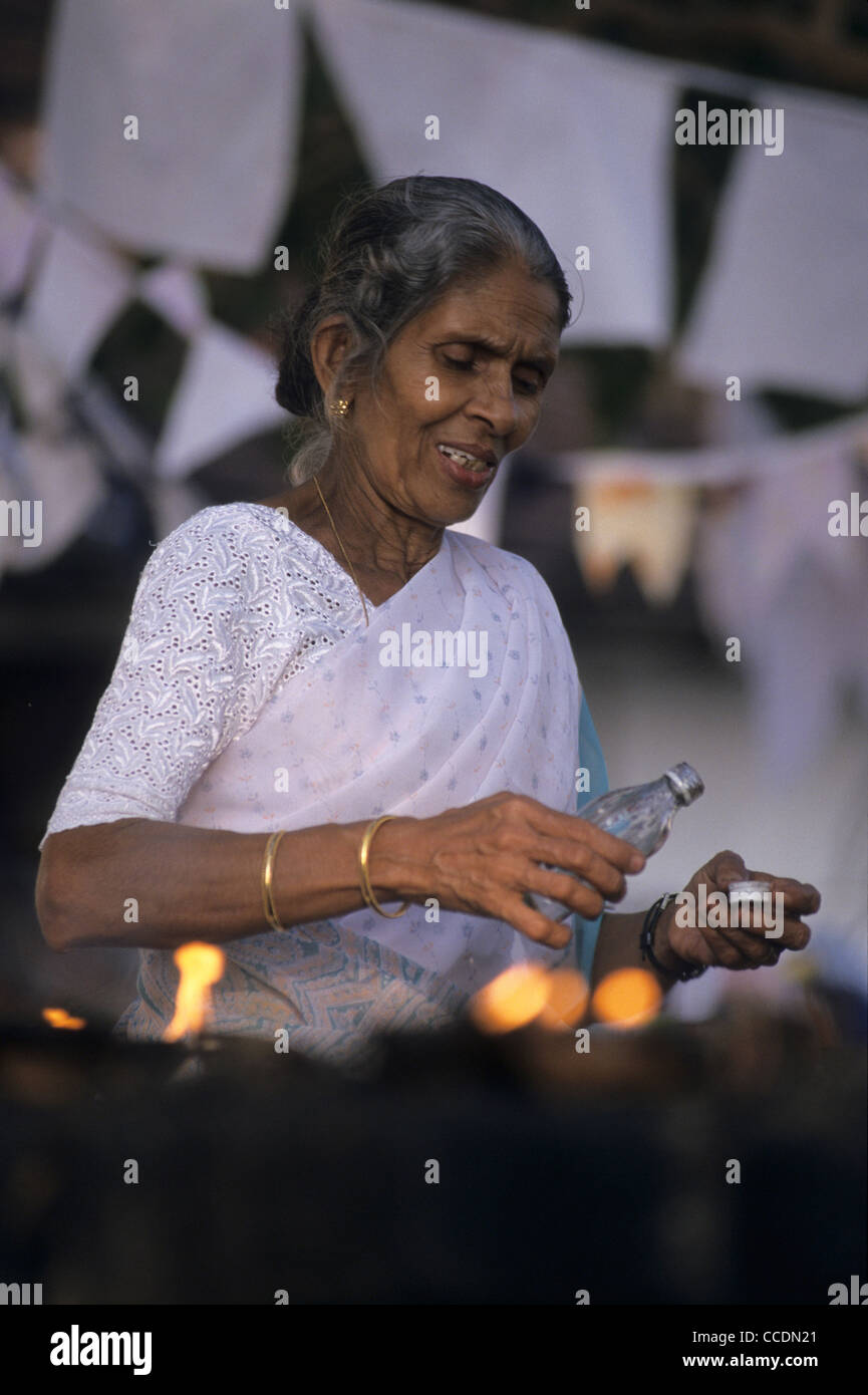 Old lady making an offering with oil lamps, cave temple, Dambulla, Sri ...