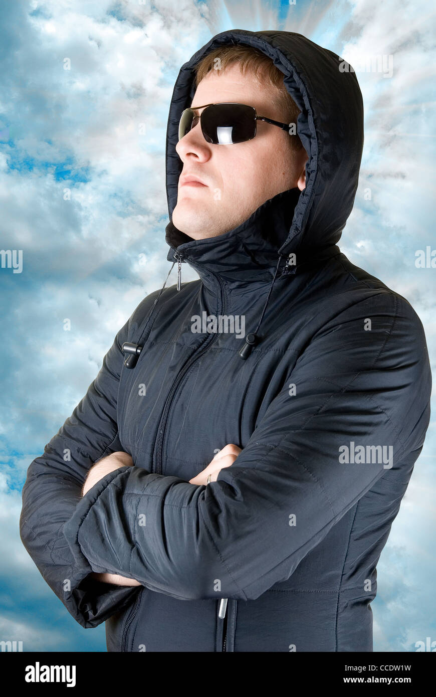 portrat of man in black sunglasses and winter jacket on blue sky ...