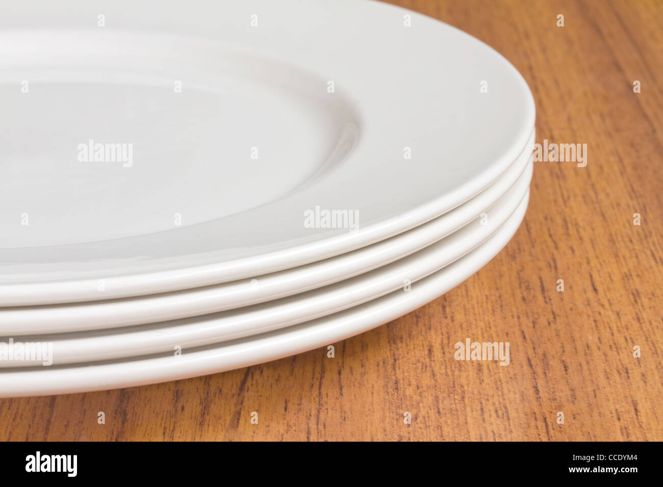 Four white plates on wooden table Stock Photo - Alamy