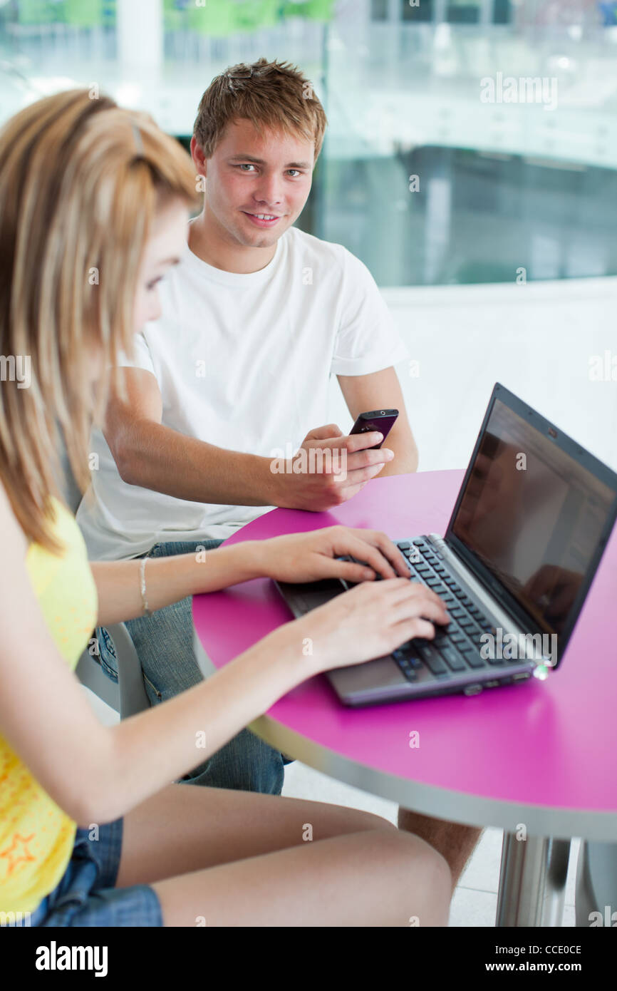 two college students having fun studying together, using a laptop ...