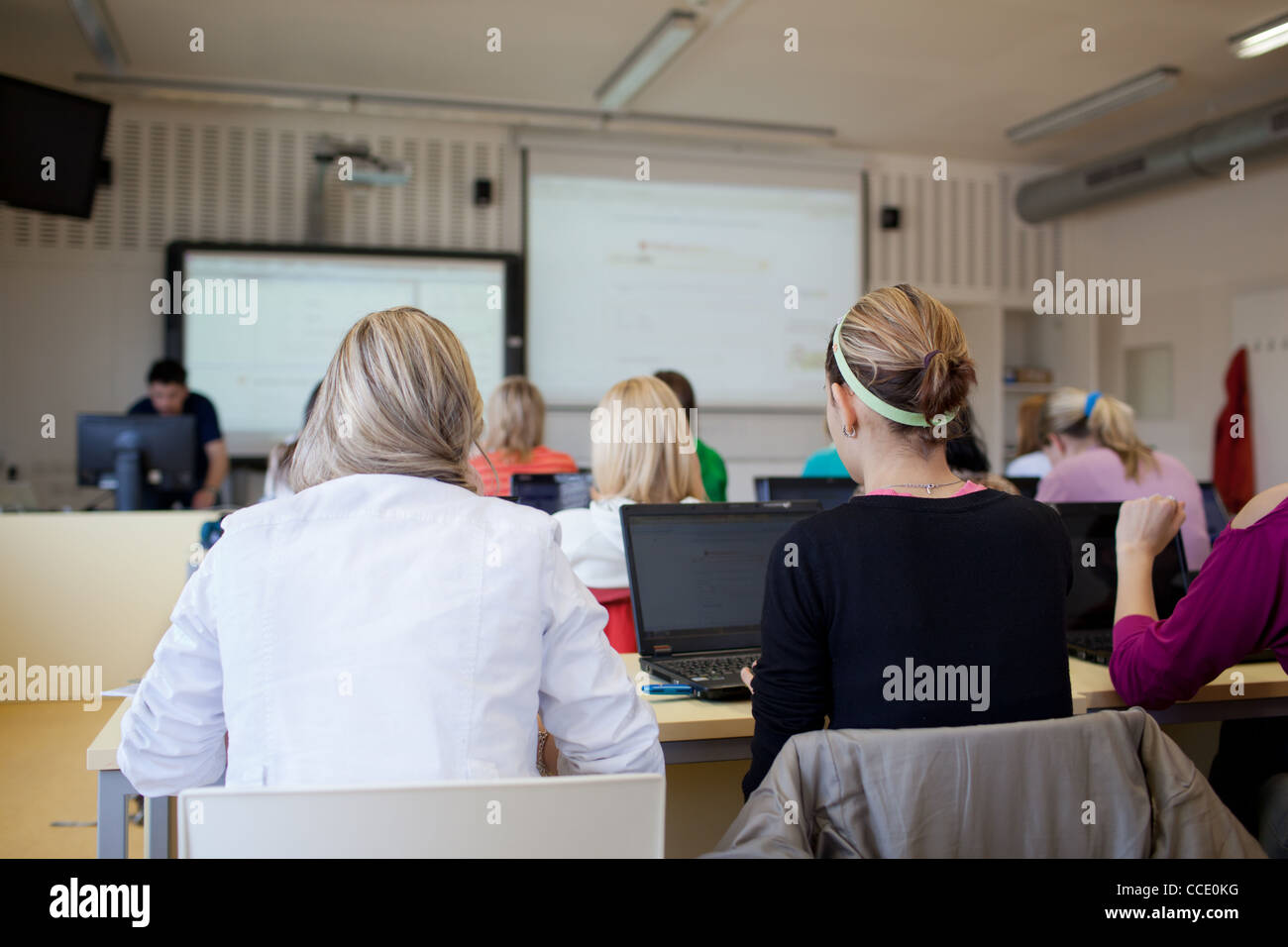 college students sitting in a classroom, using laptop computers during ...