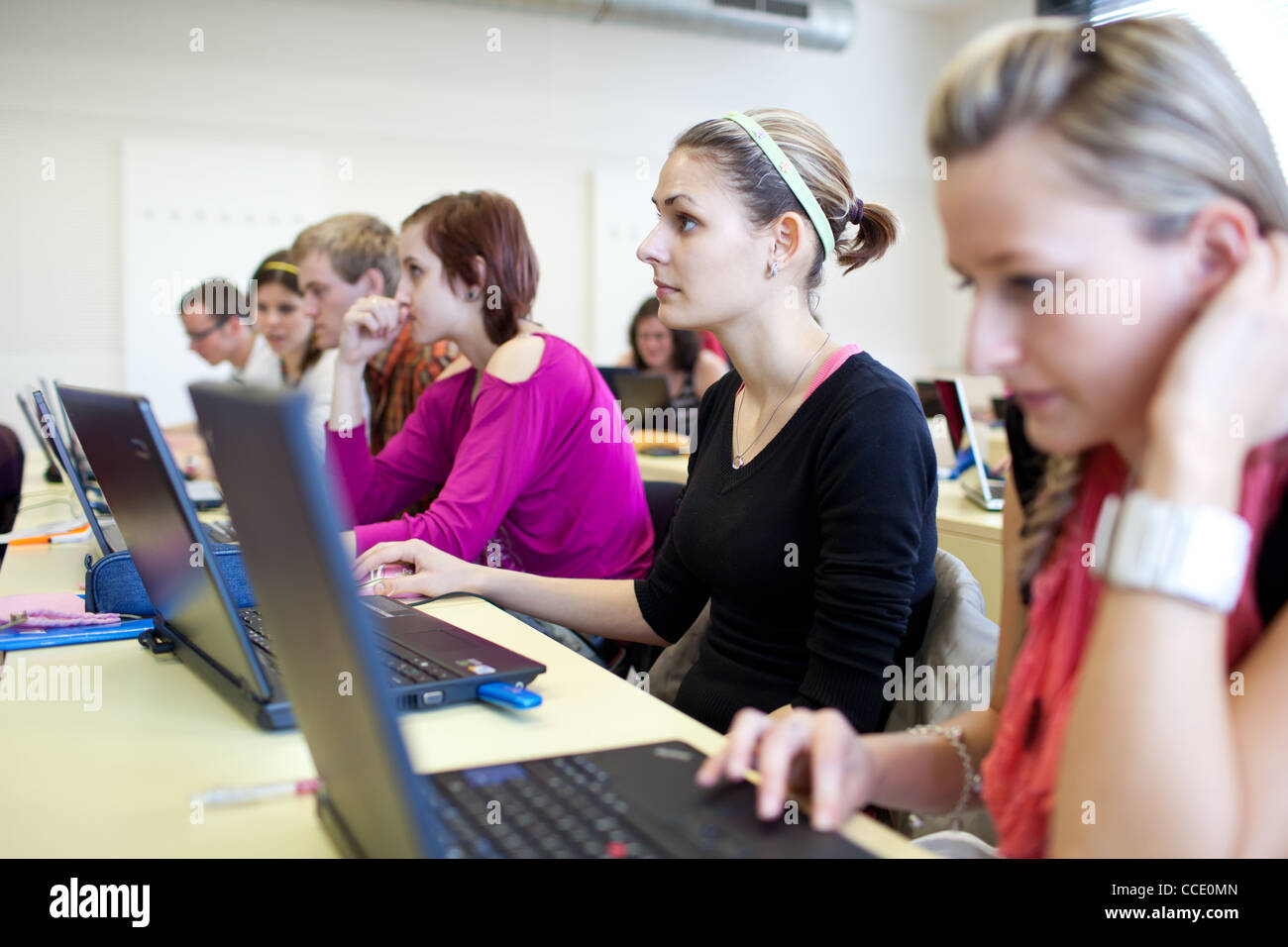 college students sitting in a classroom, using laptop computers during ...