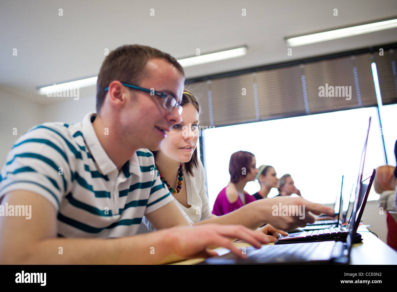 college students sitting in a classroom, using laptop computers during ...