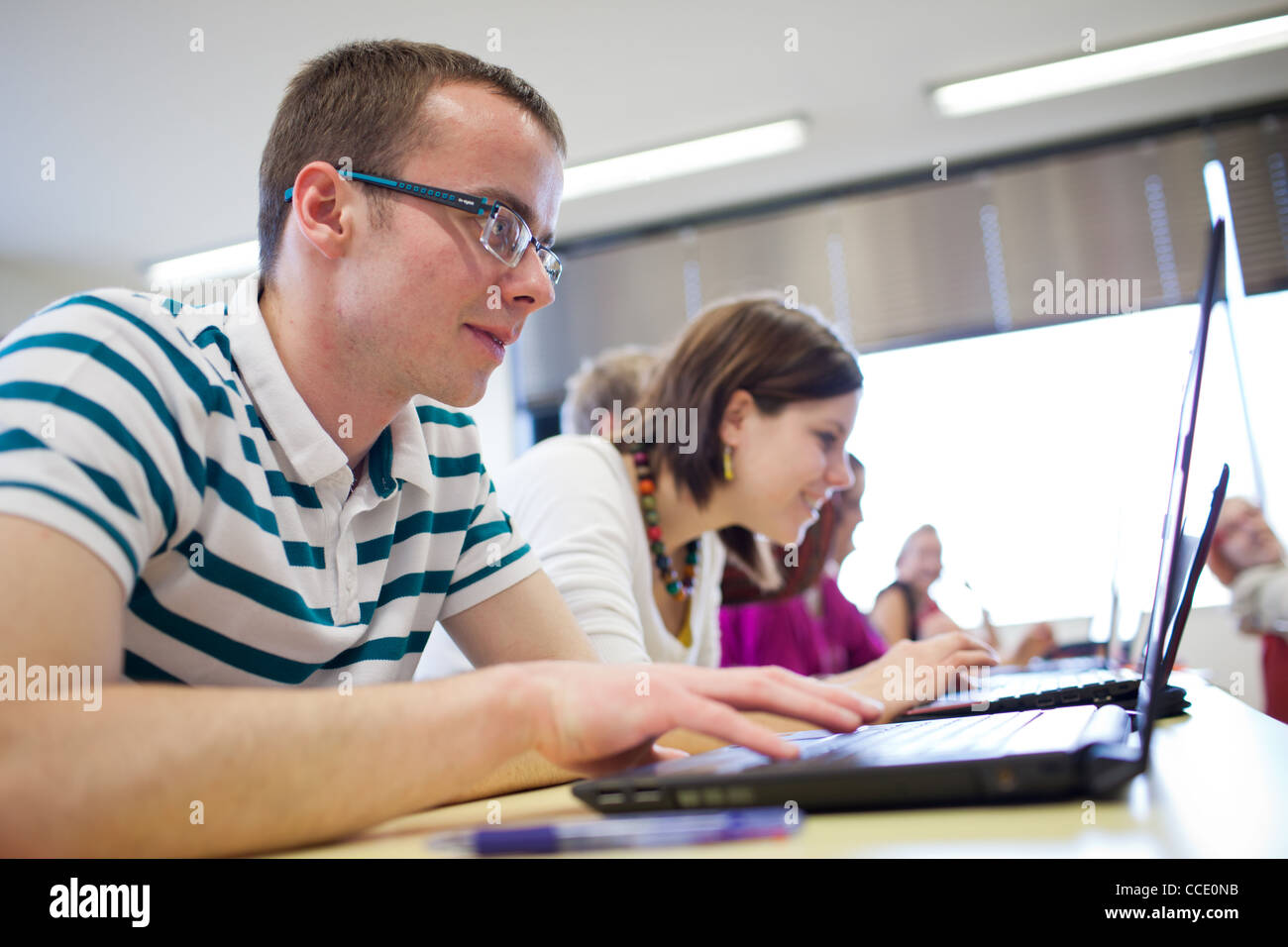 college students sitting in a classroom, using laptop computers during ...