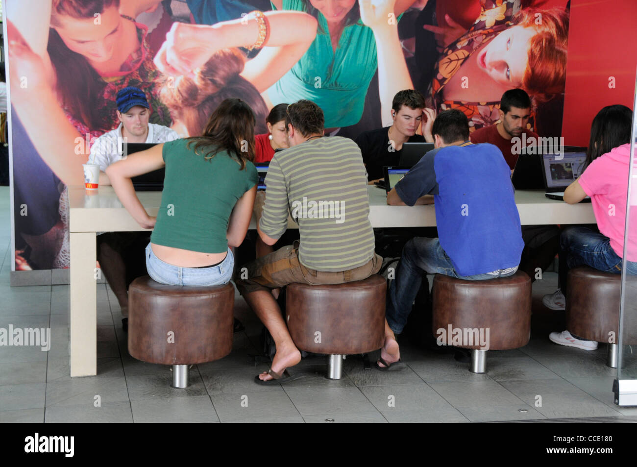 A group of young people sitting a a free wi-fi cafe using their laptops ...