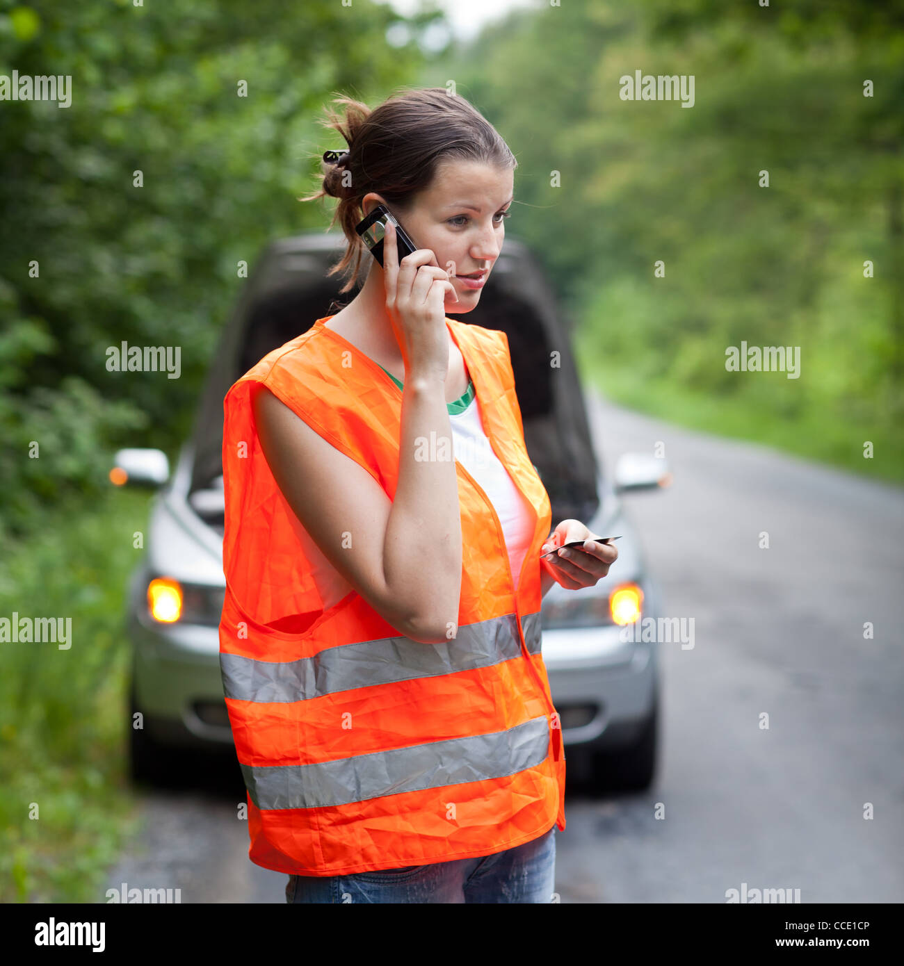 Young female driver wearing a high visibility vest, calling the ...