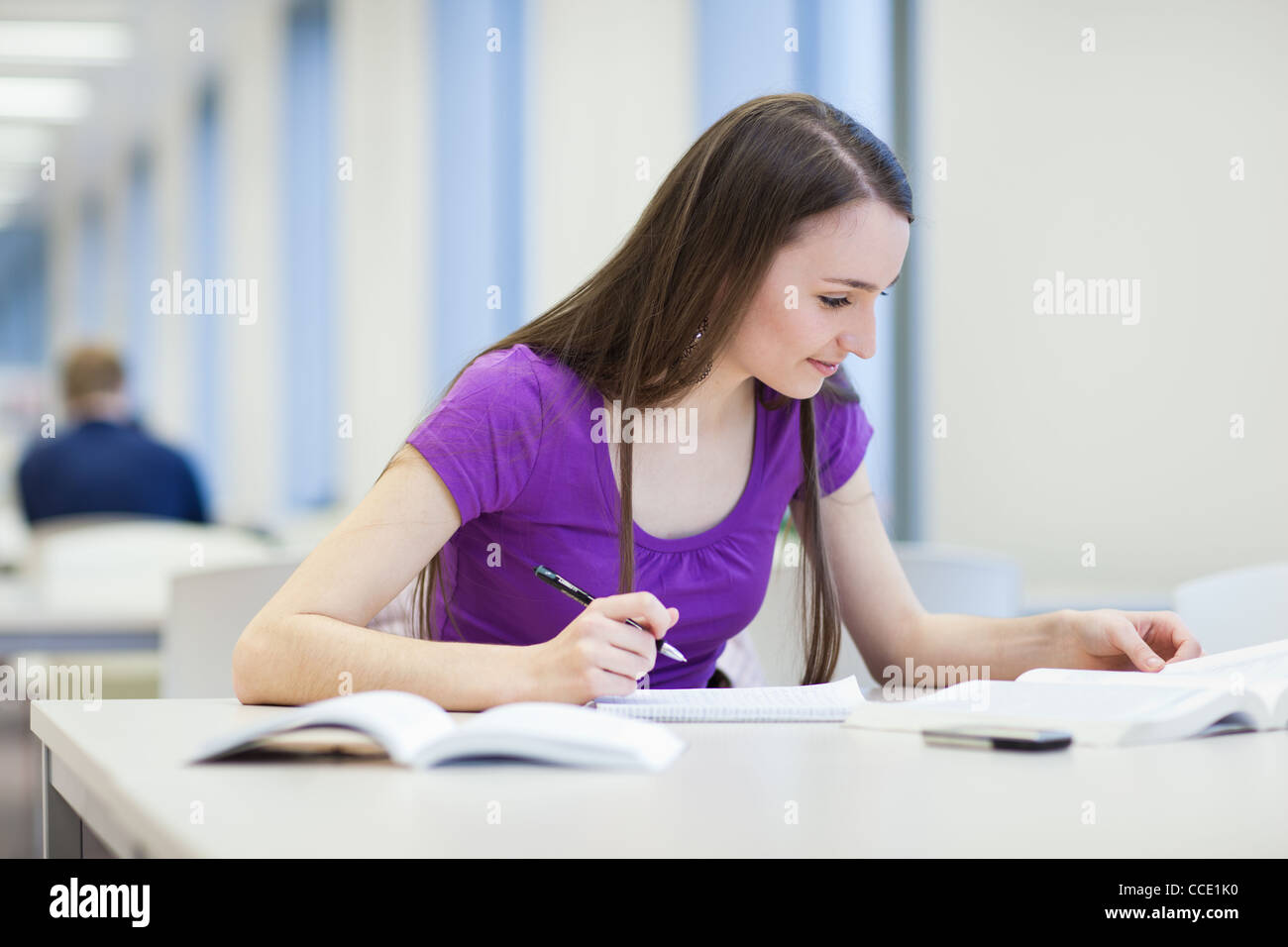 in the library - pretty female student with books working in a high ...