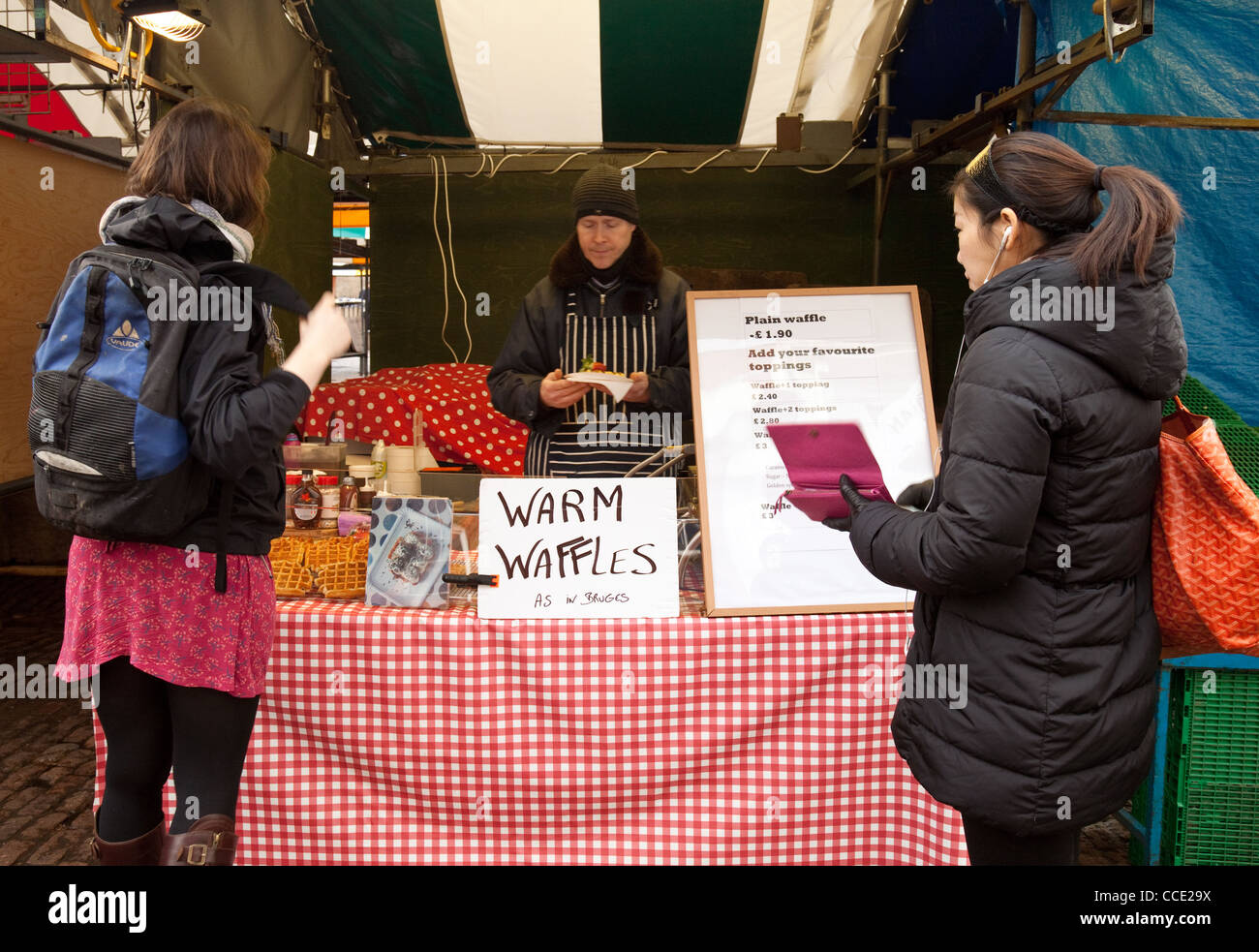 Two women buying waffles to eat from a market stall, Cambridge market ...