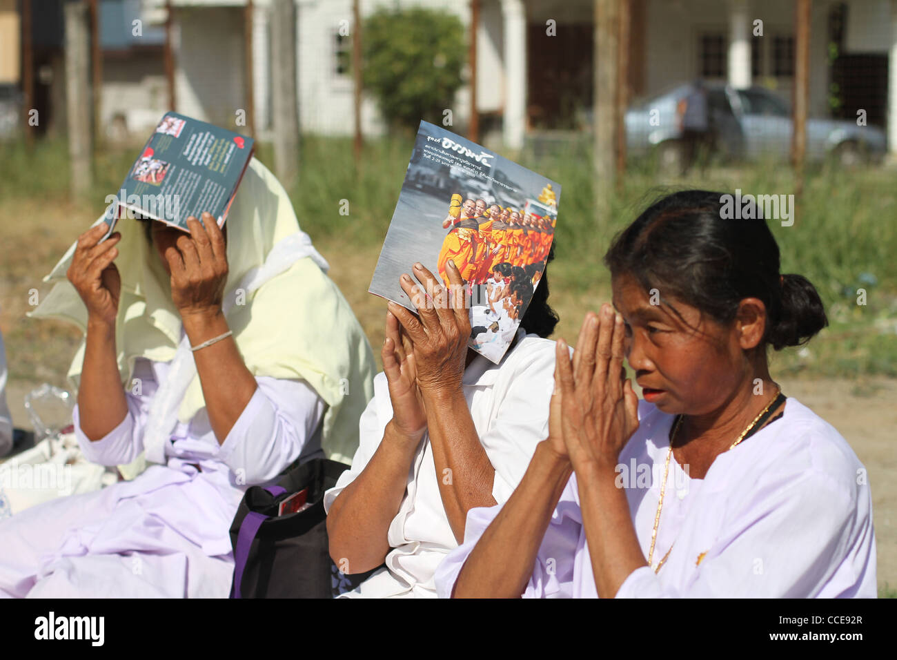 Thai female lay Buddhists gesture in respect towards Buddhist monks who ...