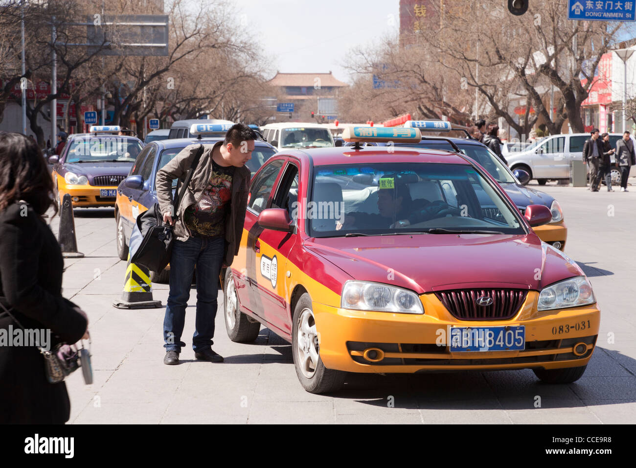 A man talking to the driver of a taxi on the streets of Beijing, China ...