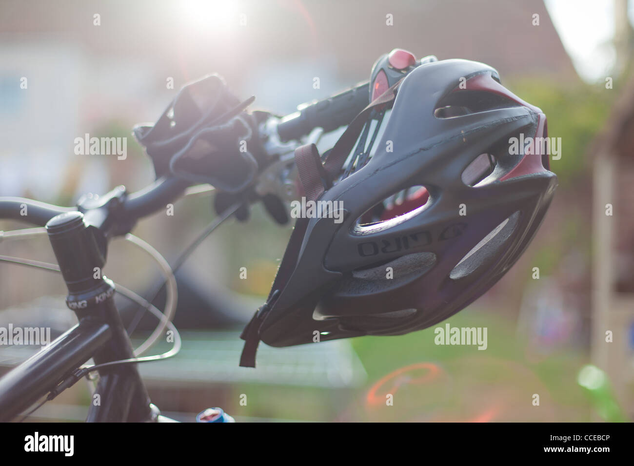 Cycle helmet hanging from a mountain bike handlebar, sun flare across ...