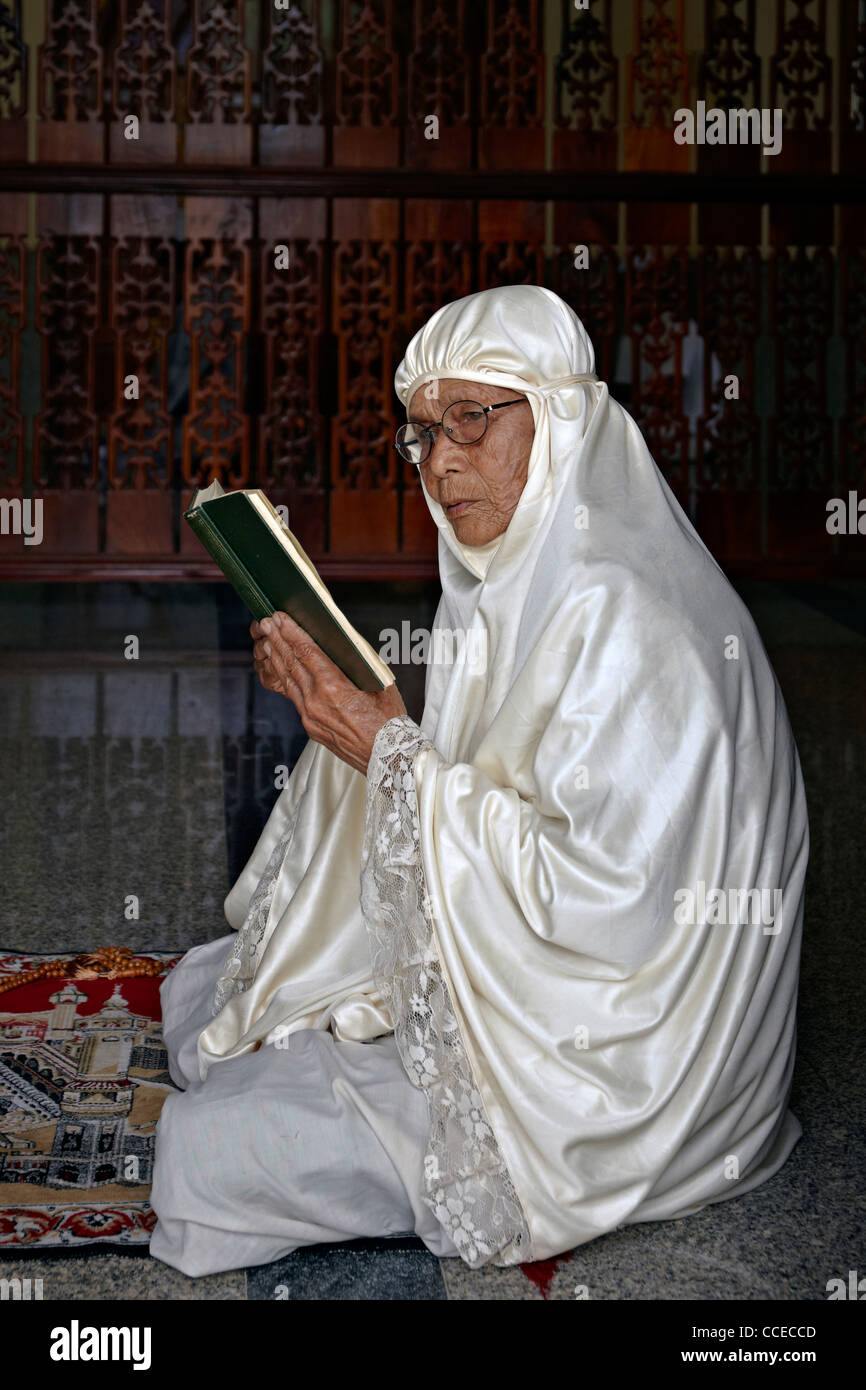 90 year old Muslim Thai woman praying and wearing a white traditional ...
