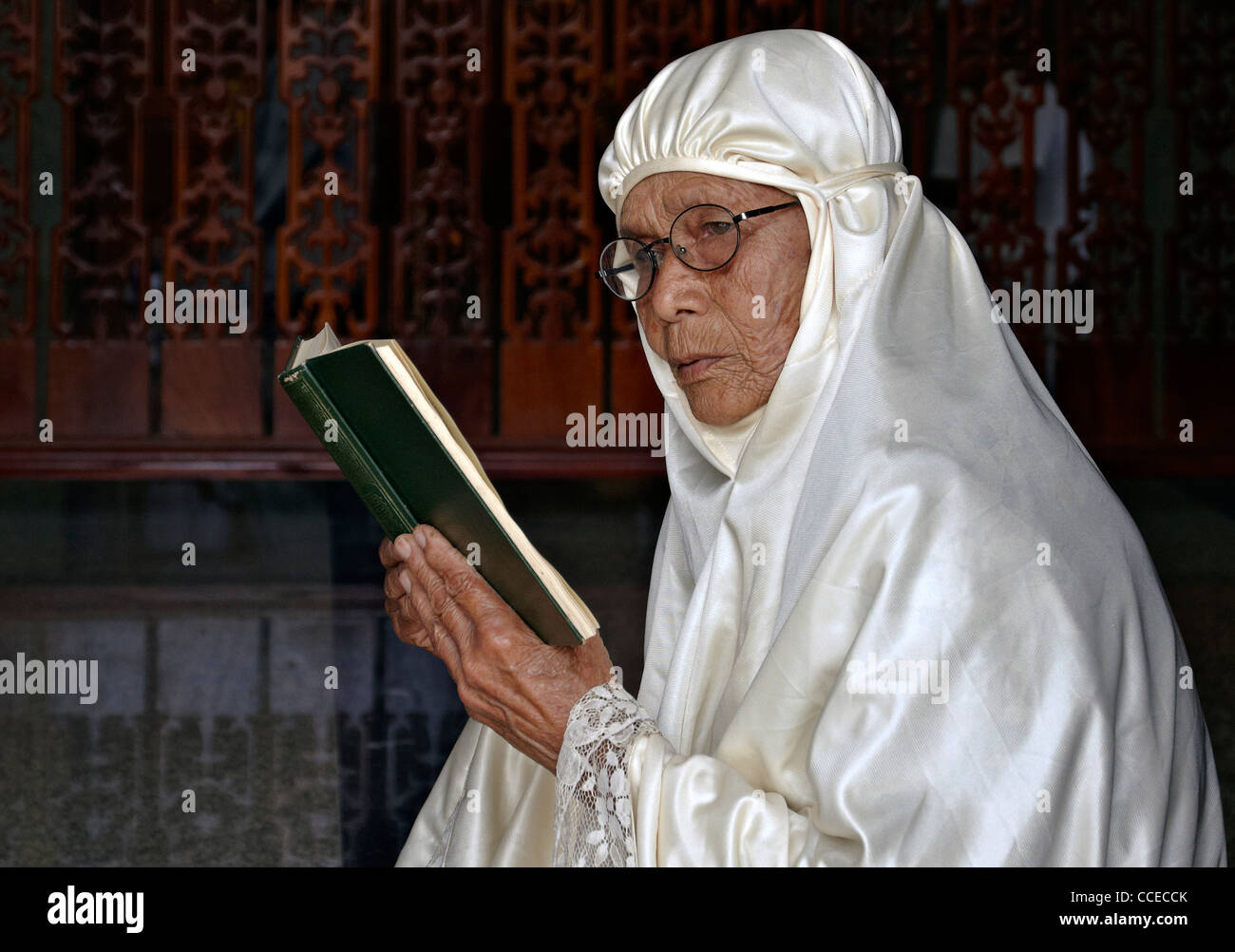 90 year old Muslim Thai woman praying and wearing a white traditional ...