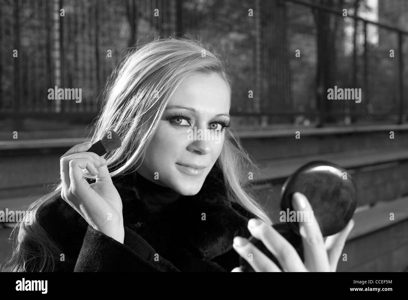 A Caucasian woman adjusts her makeup while looking in mirror Stock ...