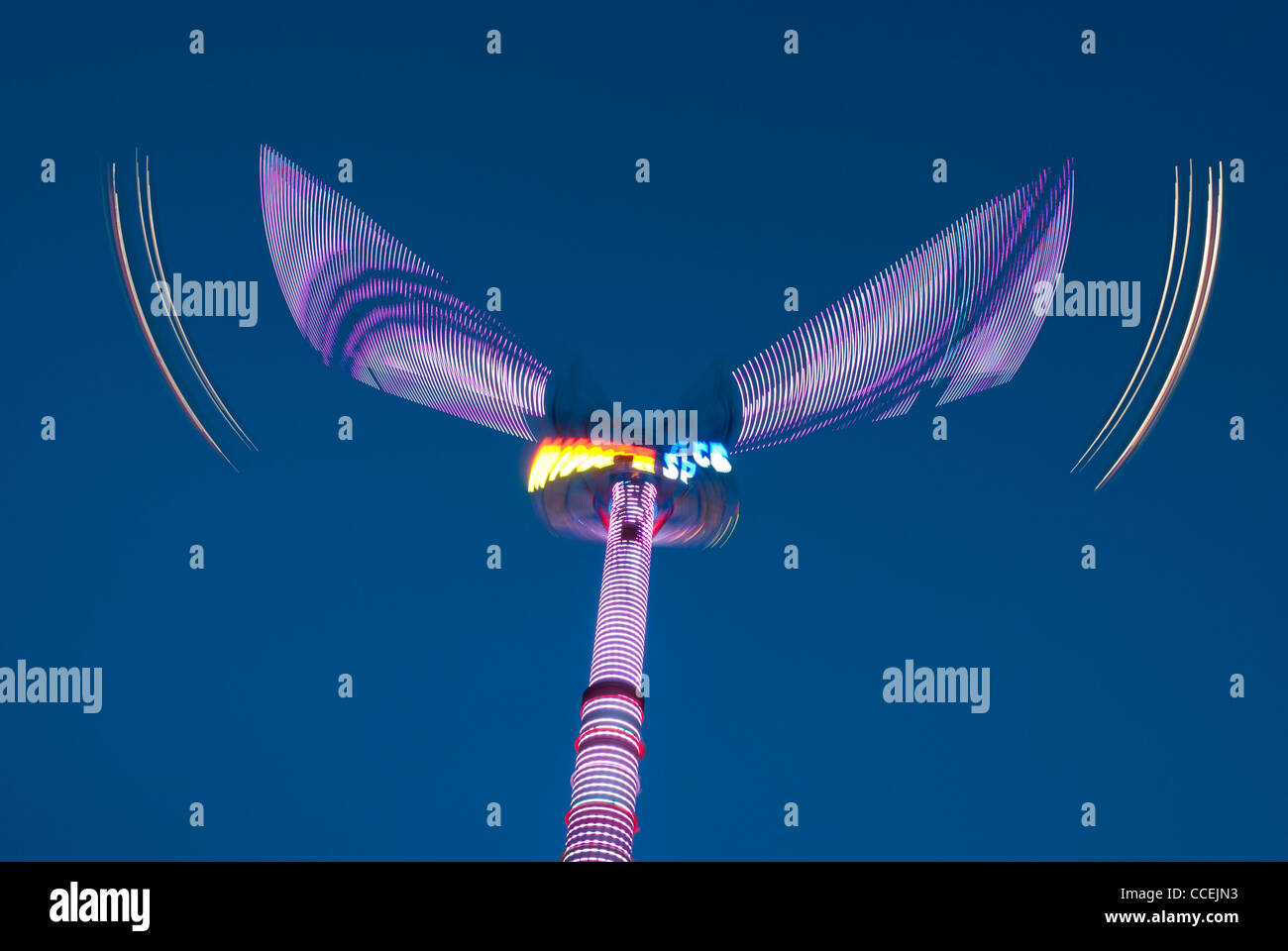 Spinning fairground thrill ride by night Stock Photo - Alamy