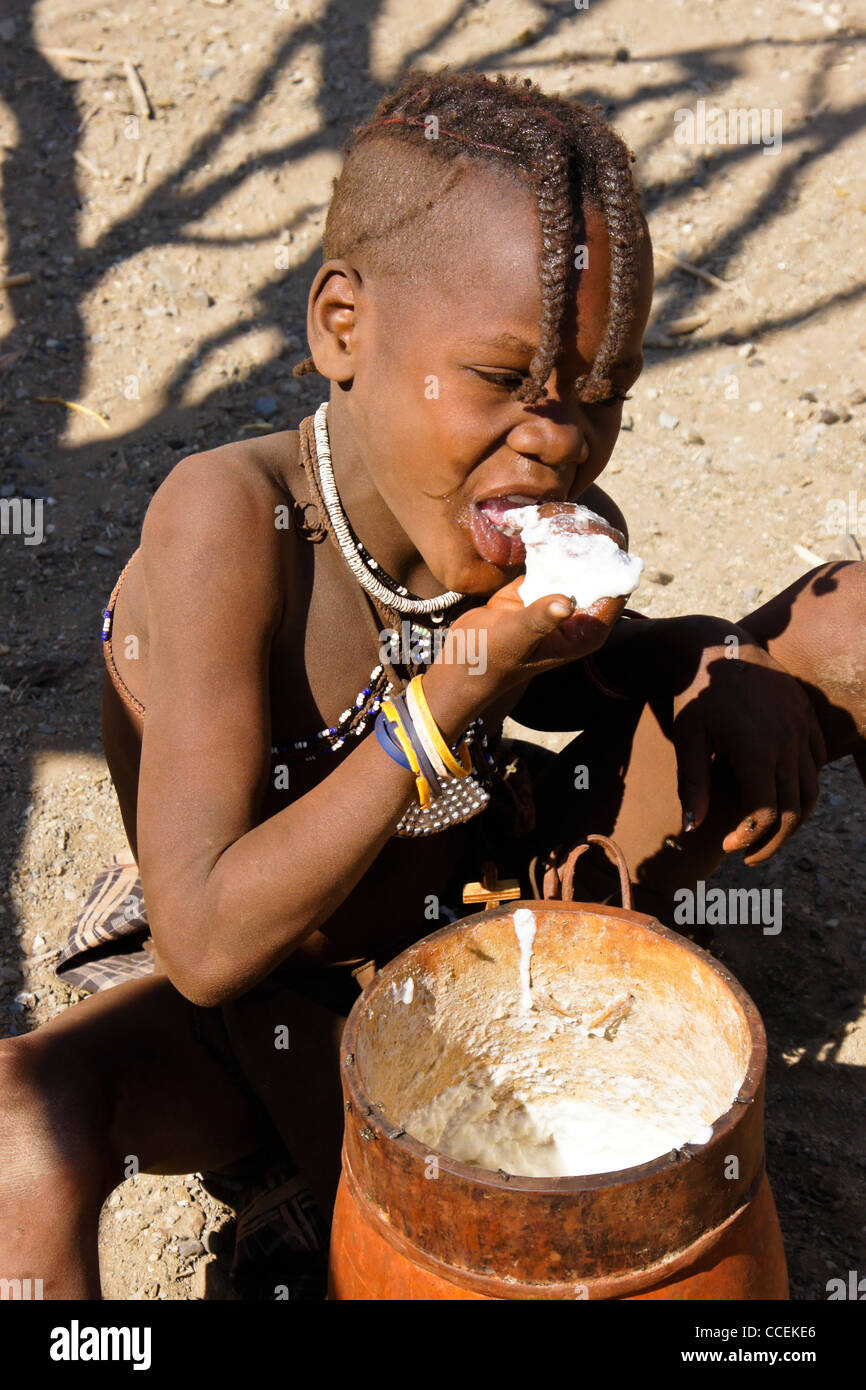 Himba girl eating maize porridge in village near Opuwo, Namibia Stock ...
