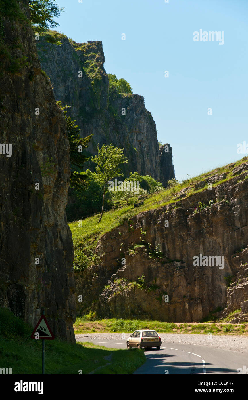 A small car driving through Cheddar Gorge on a very sunny day in early ...