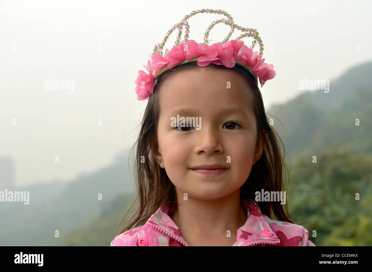 A beautiful young girl wearing a princess crown looks into the camera ...