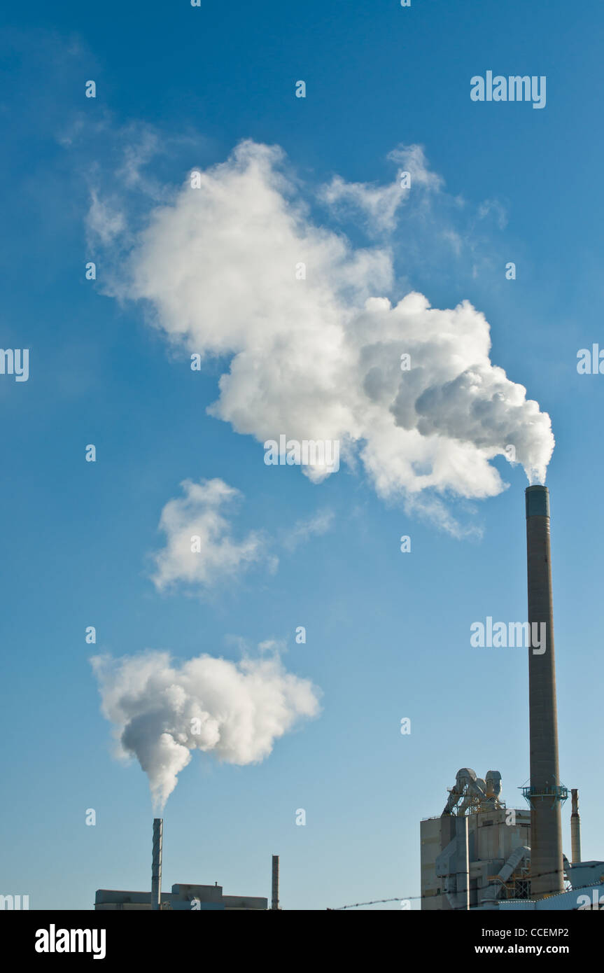A manufacturing facility pumps smoke into the air from two smokestacks ...