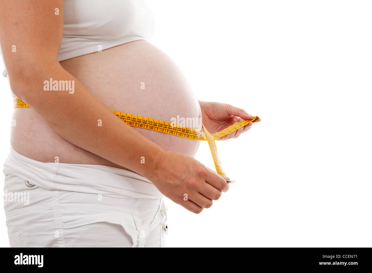 Measuring pregnant belly in closeup over white background Stock Photo ...